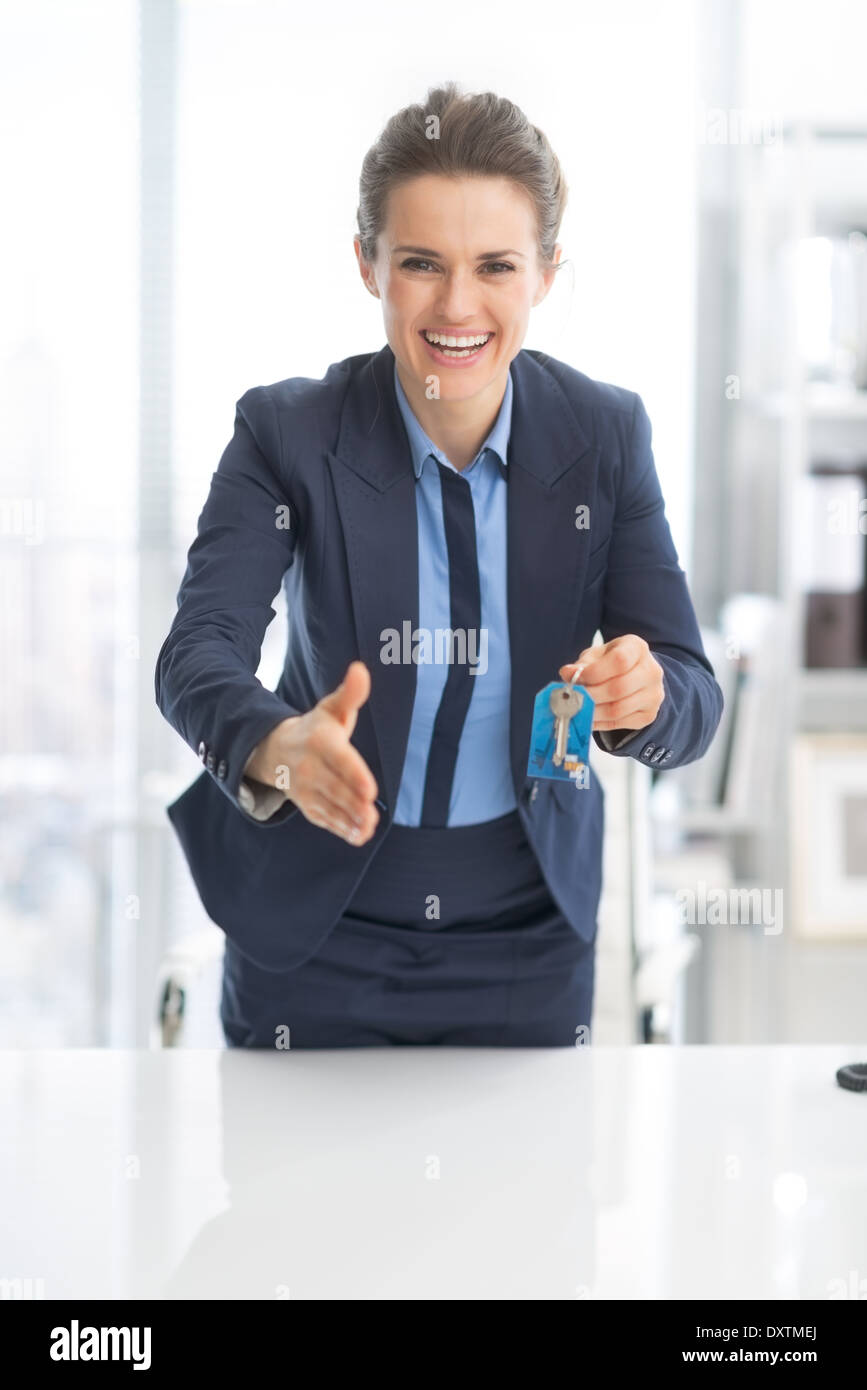 Happy business woman giving keys and stretching hand for handshake ...
