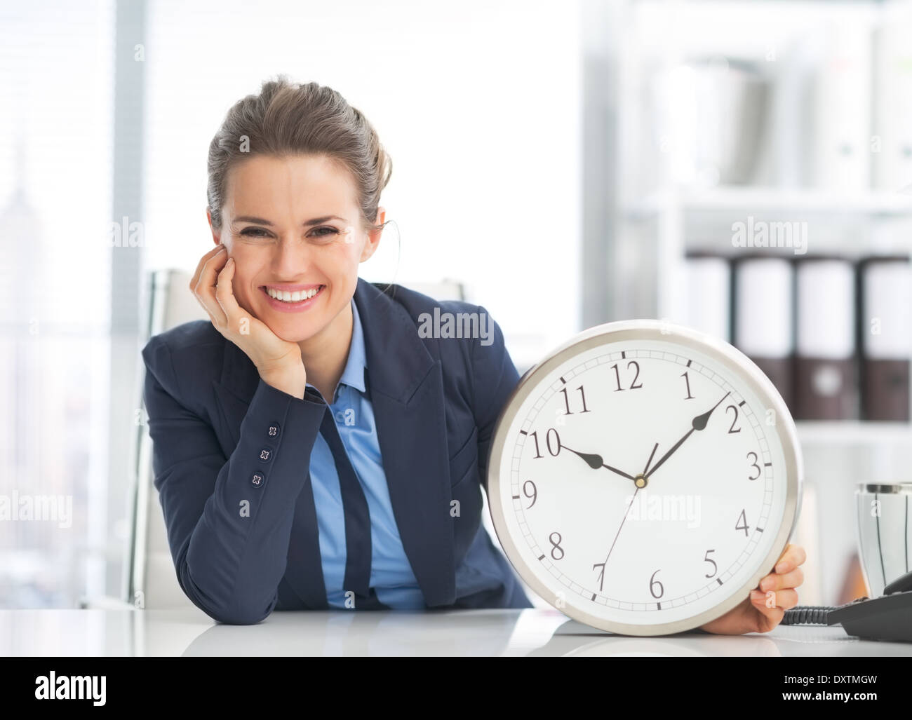 Happy business woman showing clock Stock Photo - Alamy
