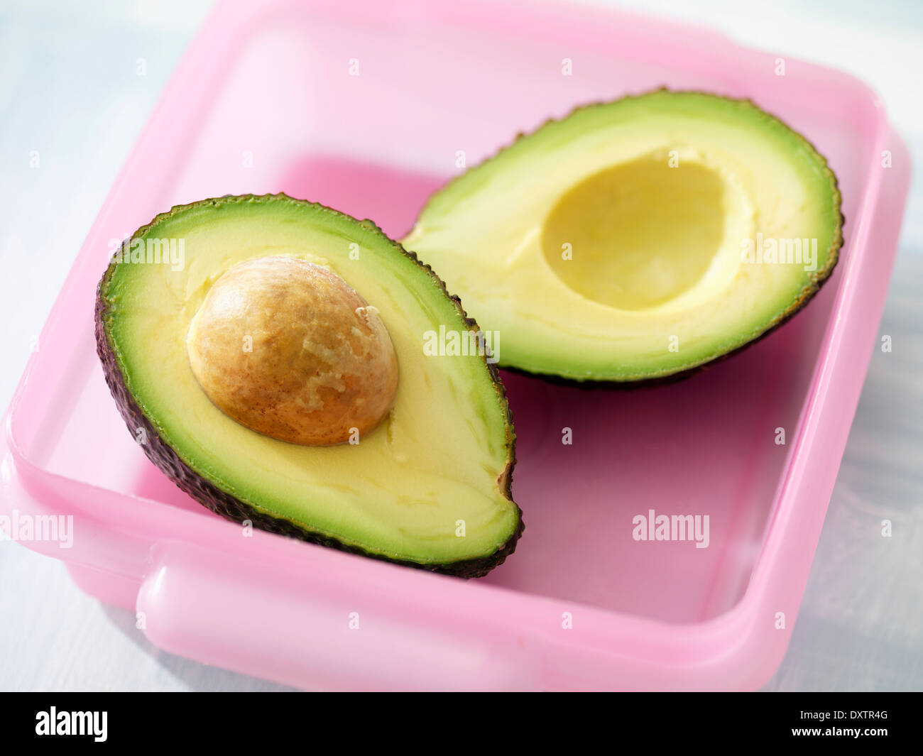 Avocado cut in half in a plastic container Stock Photo - Alamy