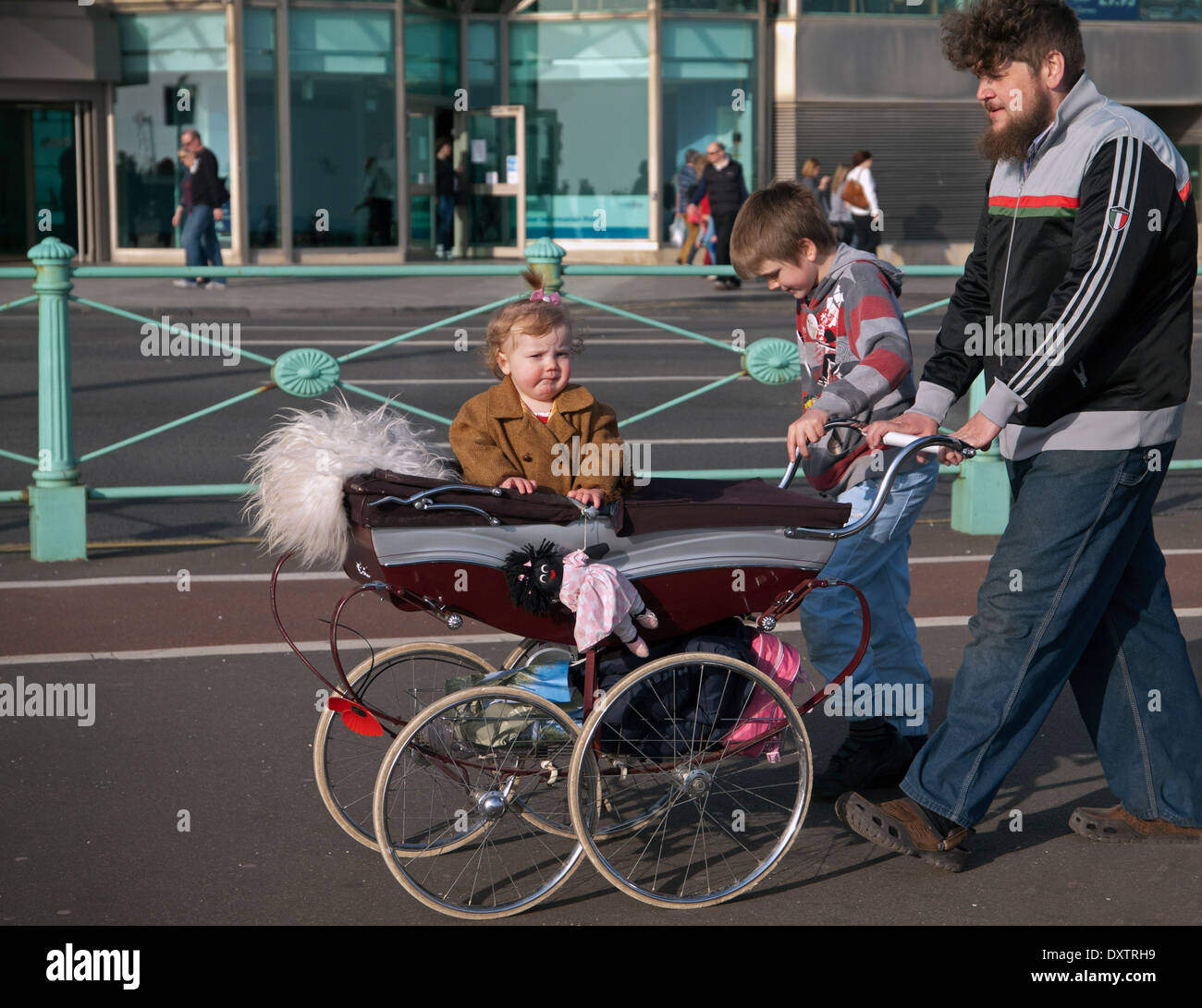 A father pushes his daughter's pram along the Brighton seafront Stock ...