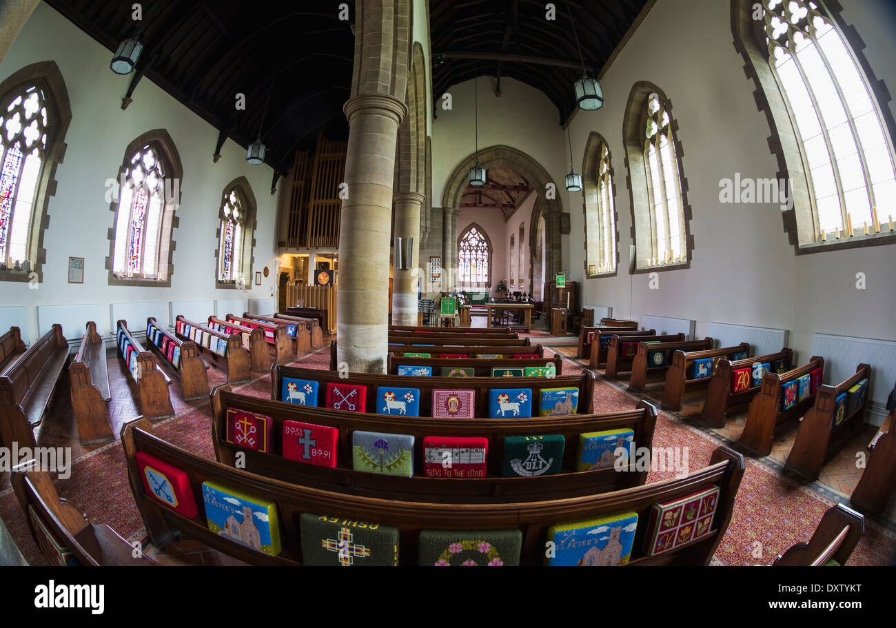 Interior of a church with colourful times on the backs on wooden pews ...