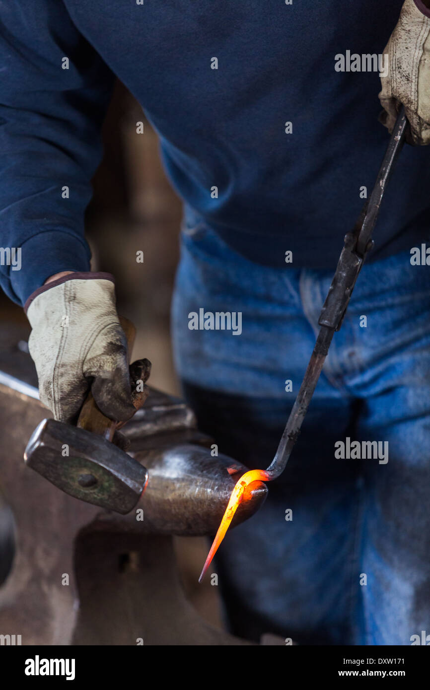 blacksmith bending hot iron on the anvil Stock Photo - Alamy