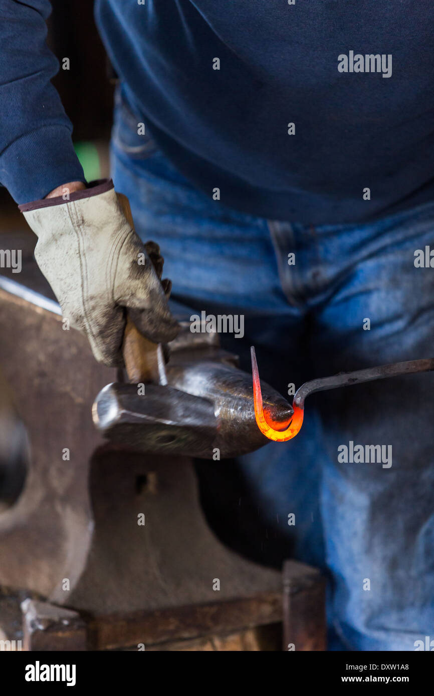 blacksmith bending hot iron on the anvil Stock Photo - Alamy
