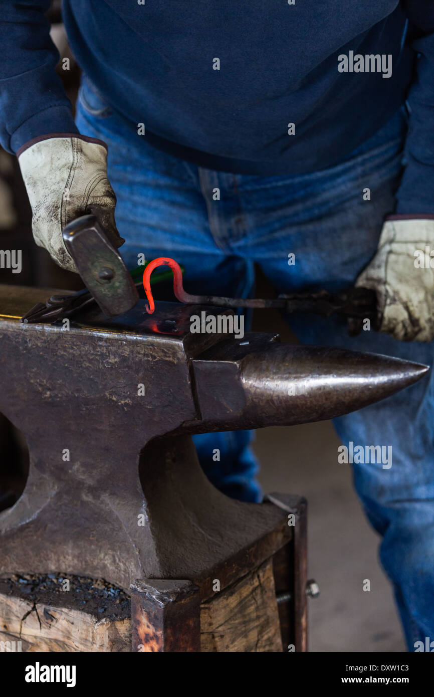 blacksmith bending hot iron on the anvil Stock Photo - Alamy