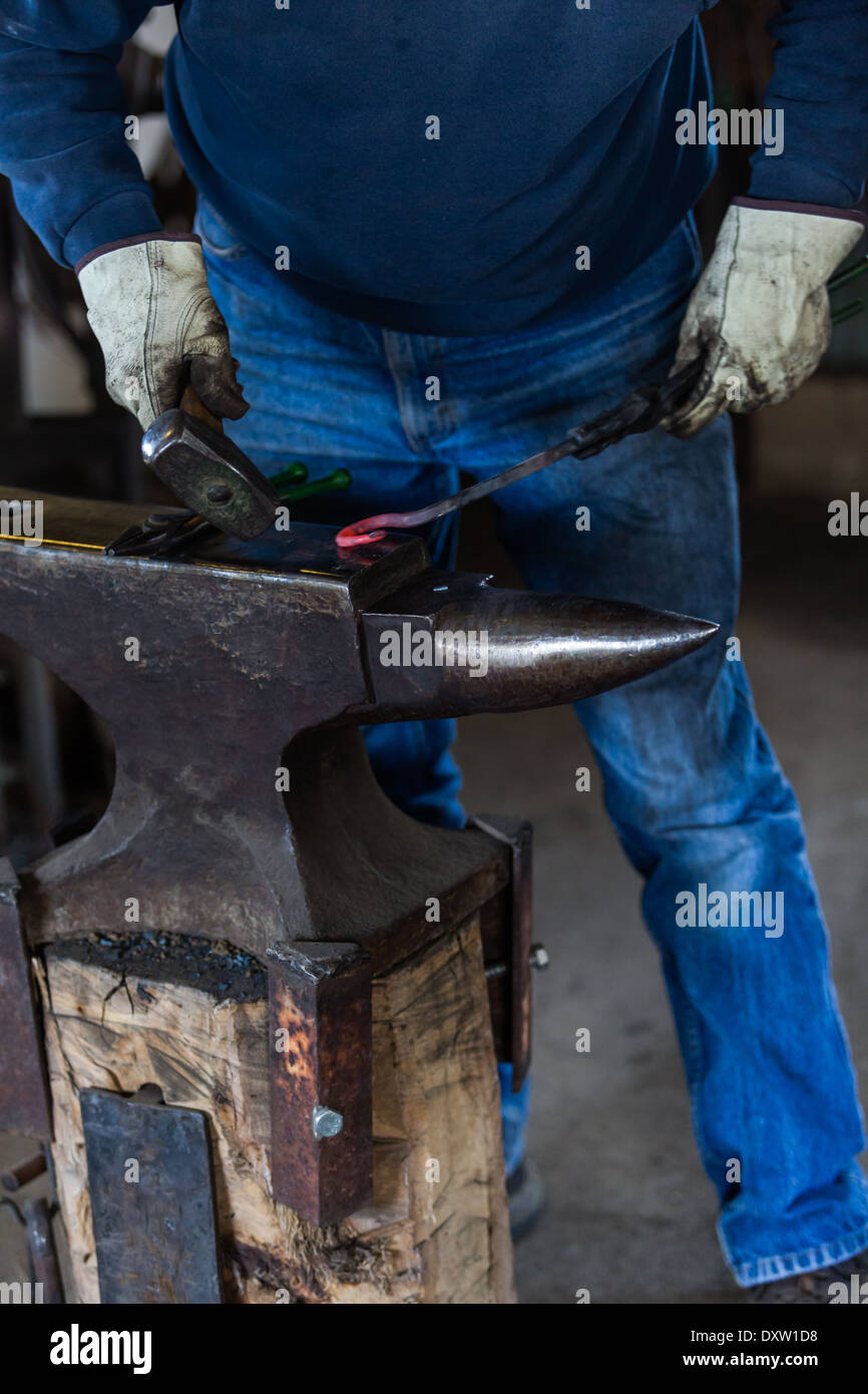 blacksmith bending hot iron on the anvil Stock Photo - Alamy