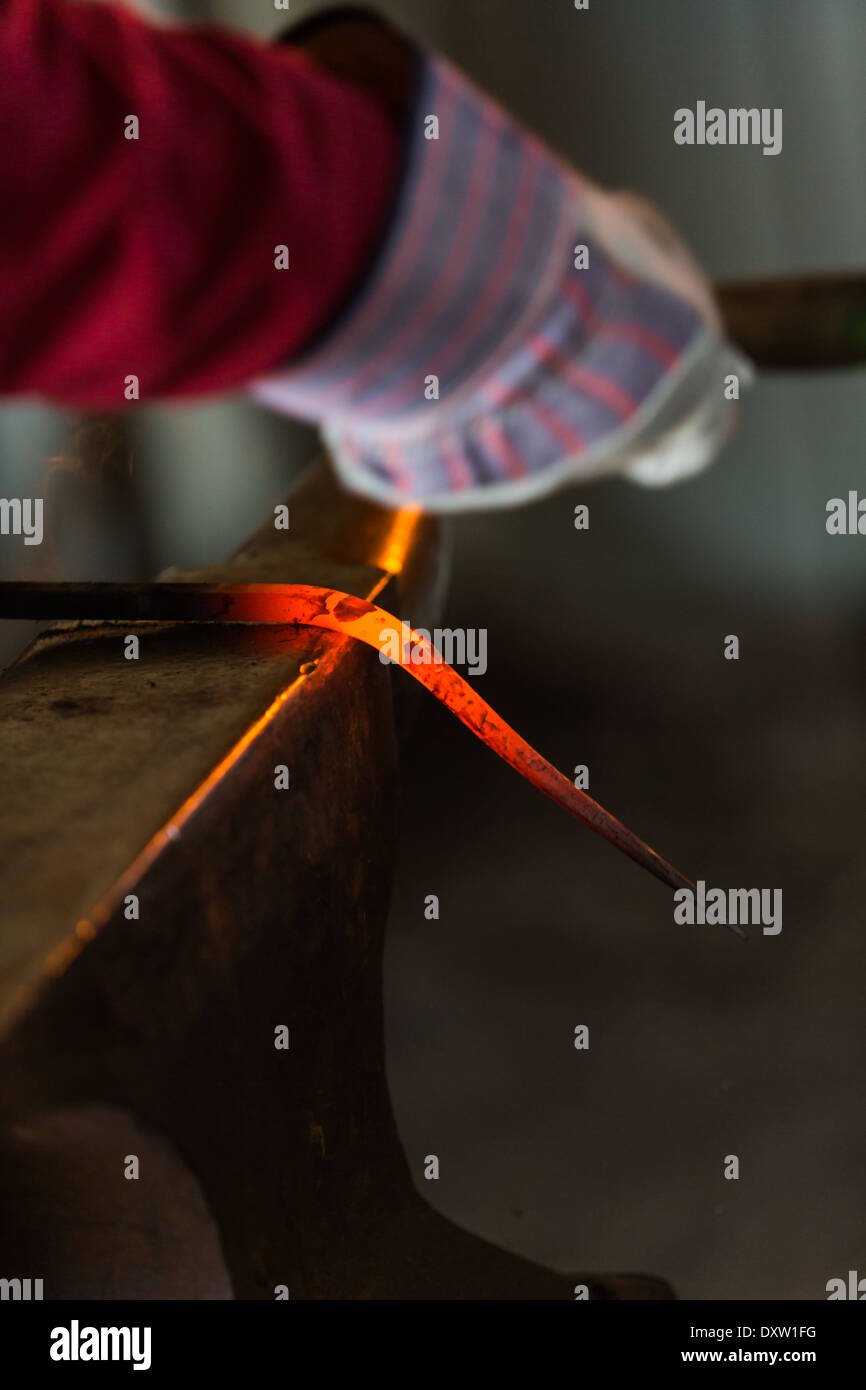 blacksmith bending hot iron on the anvil Stock Photo - Alamy