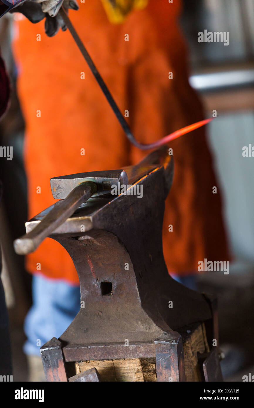 blacksmith bending hot iron on the anvil Stock Photo - Alamy