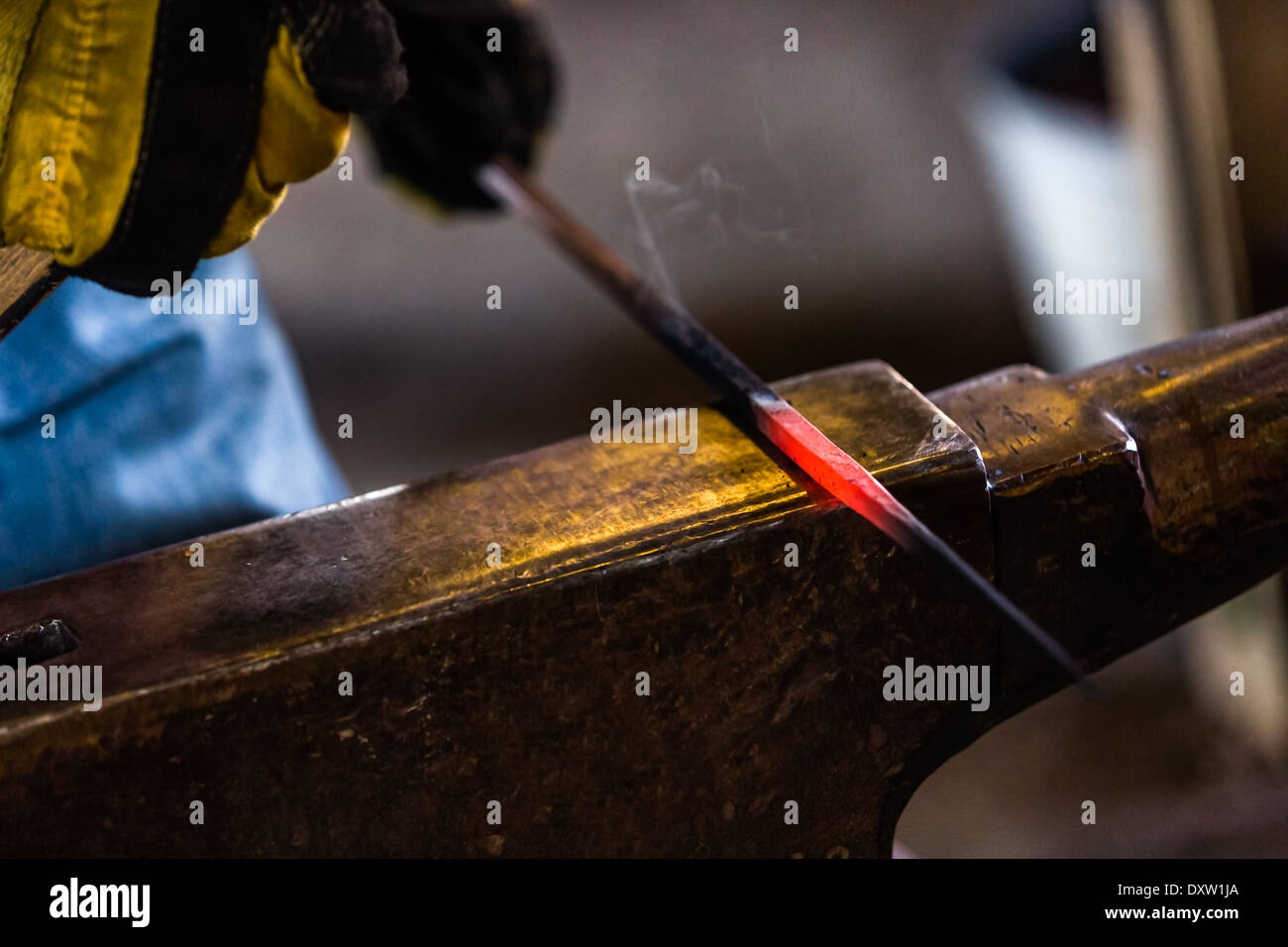 blacksmith bending hot iron on the anvil Stock Photo - Alamy