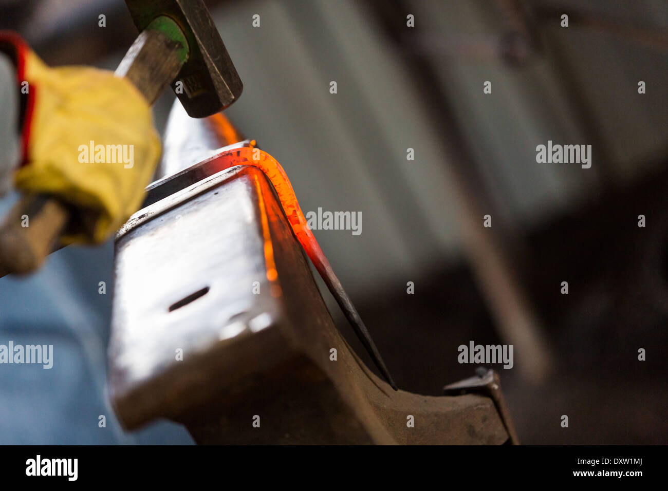 blacksmith bending hot iron on the anvil Stock Photo - Alamy