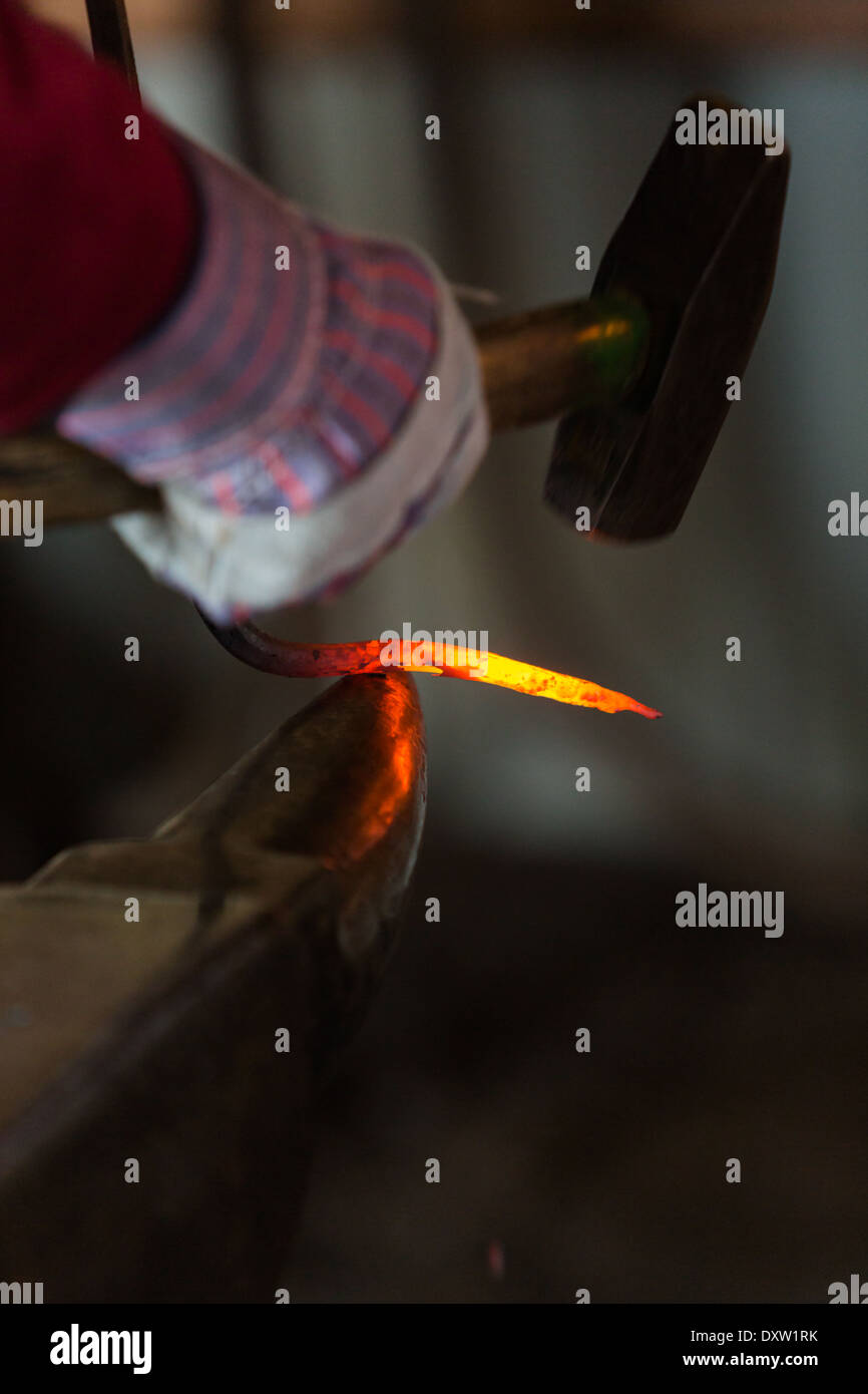 blacksmith bending hot iron on the anvil Stock Photo - Alamy
