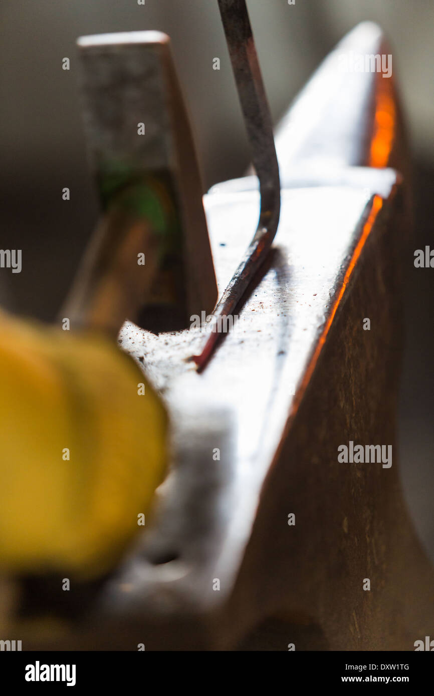 blacksmith bending hot iron on the anvil Stock Photo - Alamy