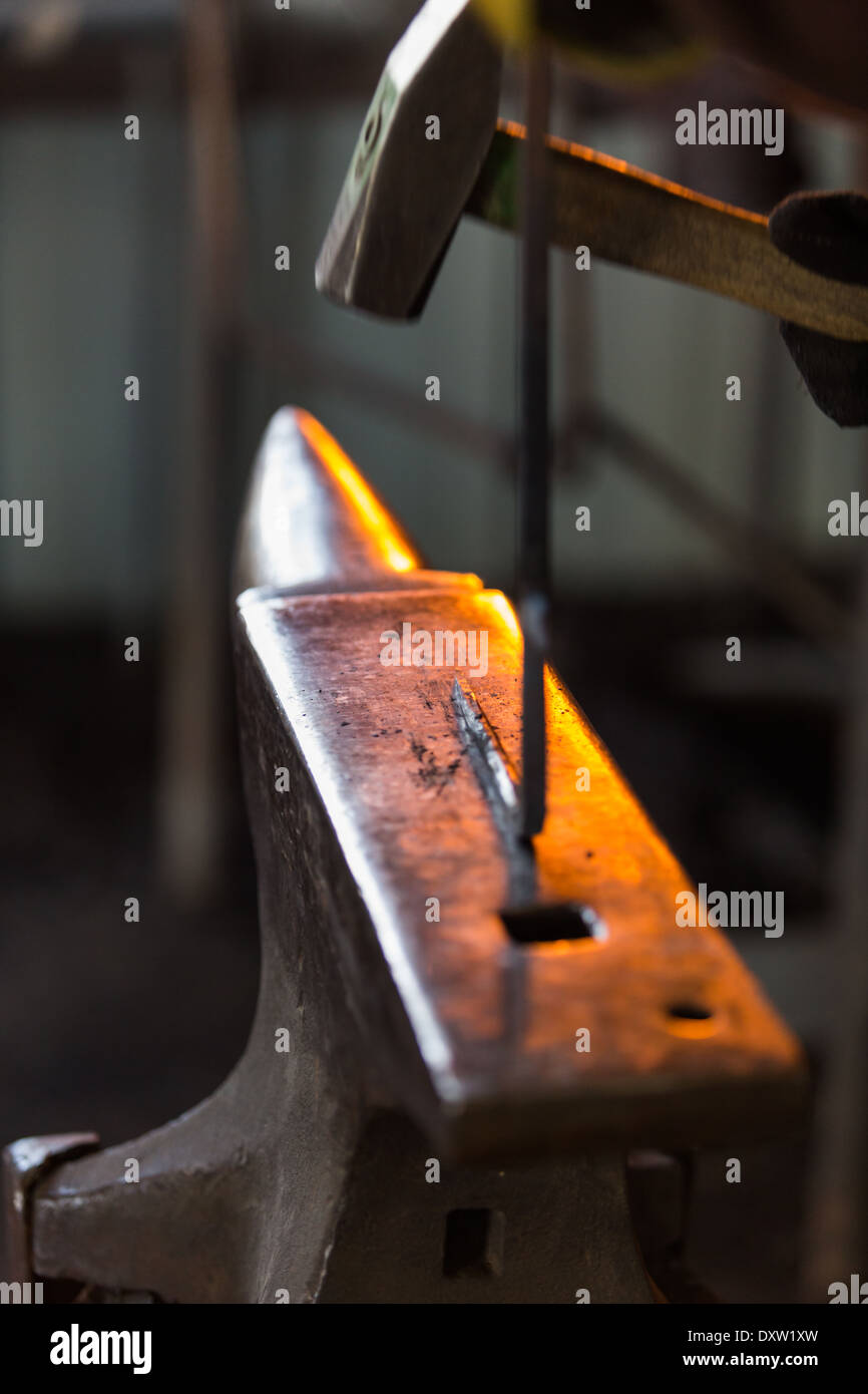 blacksmith bending hot iron on the anvil Stock Photo - Alamy