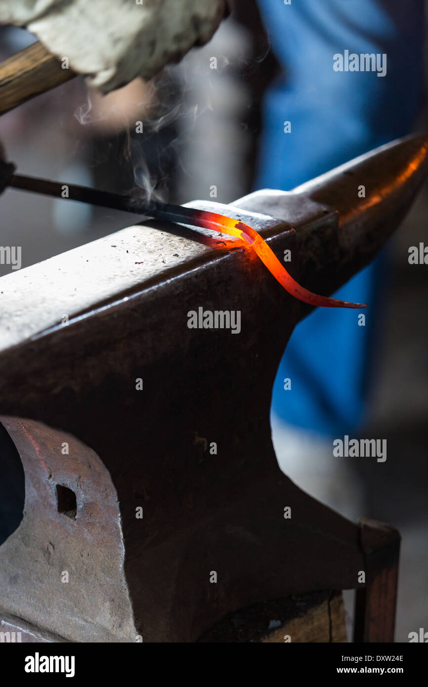 blacksmith bending hot iron on the anvil Stock Photo - Alamy