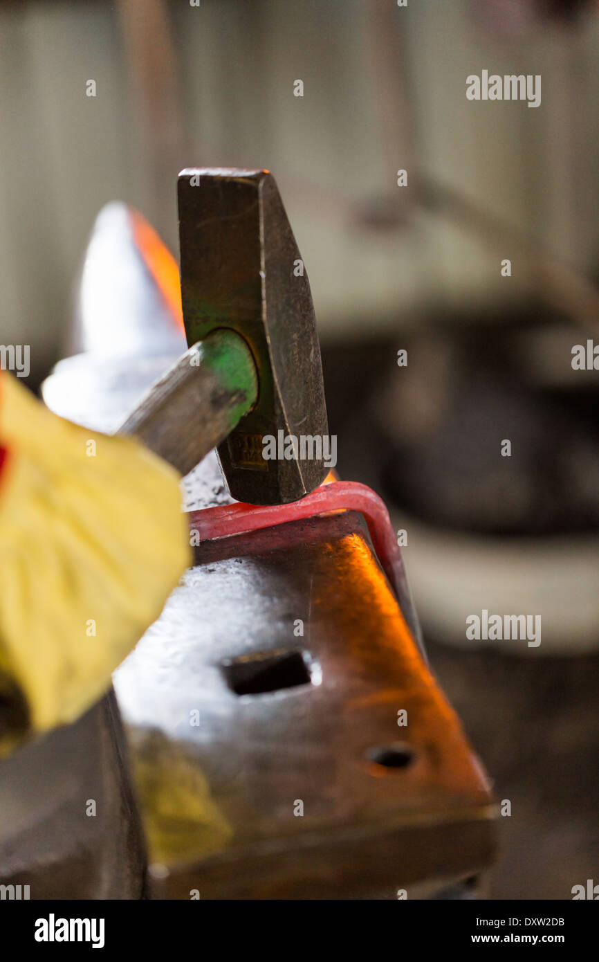 blacksmith bending hot iron on the anvil Stock Photo - Alamy