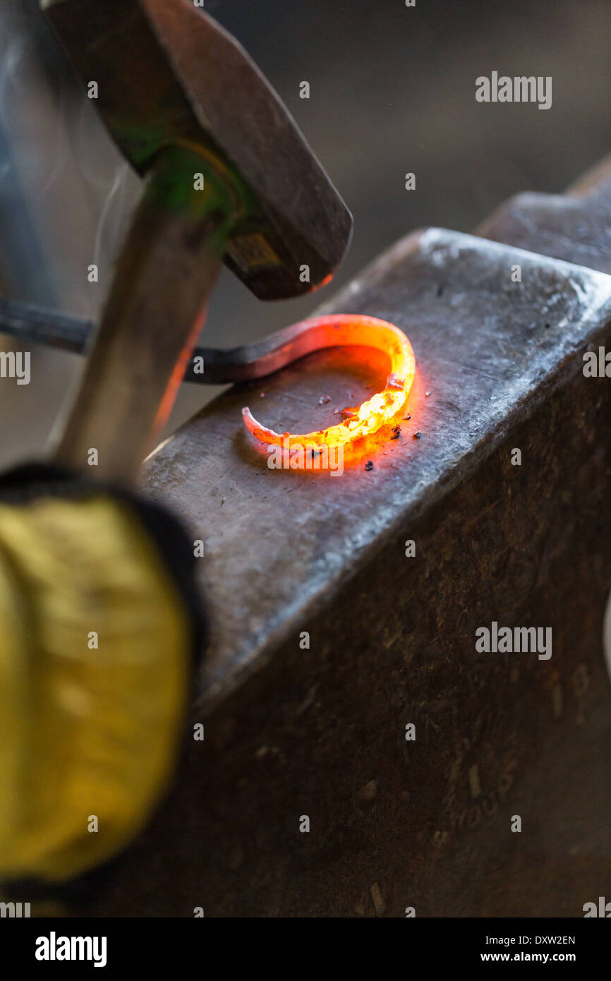 blacksmith bending hot iron on the anvil Stock Photo - Alamy