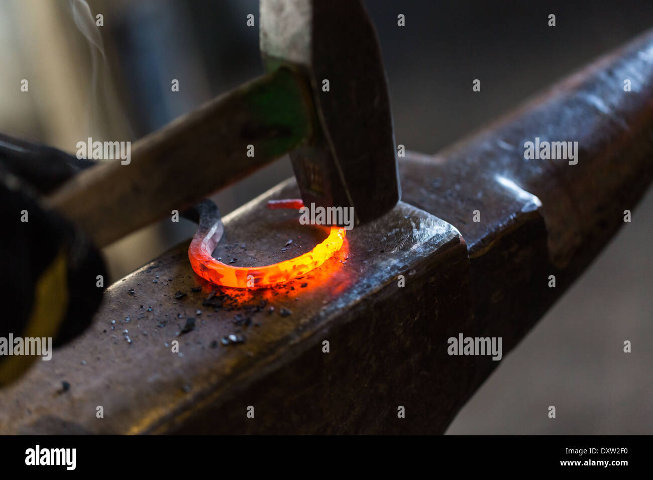 blacksmith bending hot iron on the anvil Stock Photo - Alamy