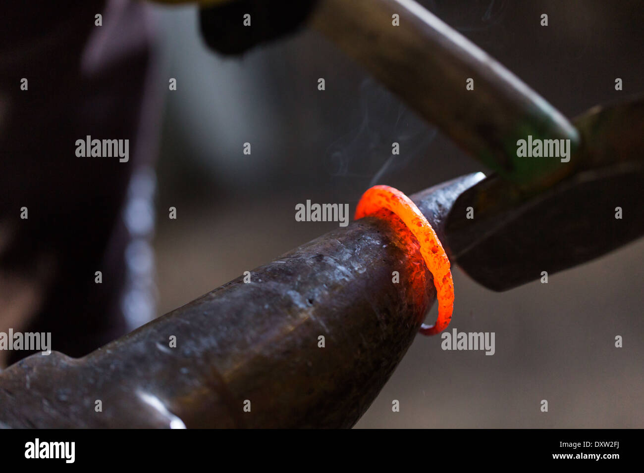 blacksmith bending hot iron on the anvil Stock Photo - Alamy