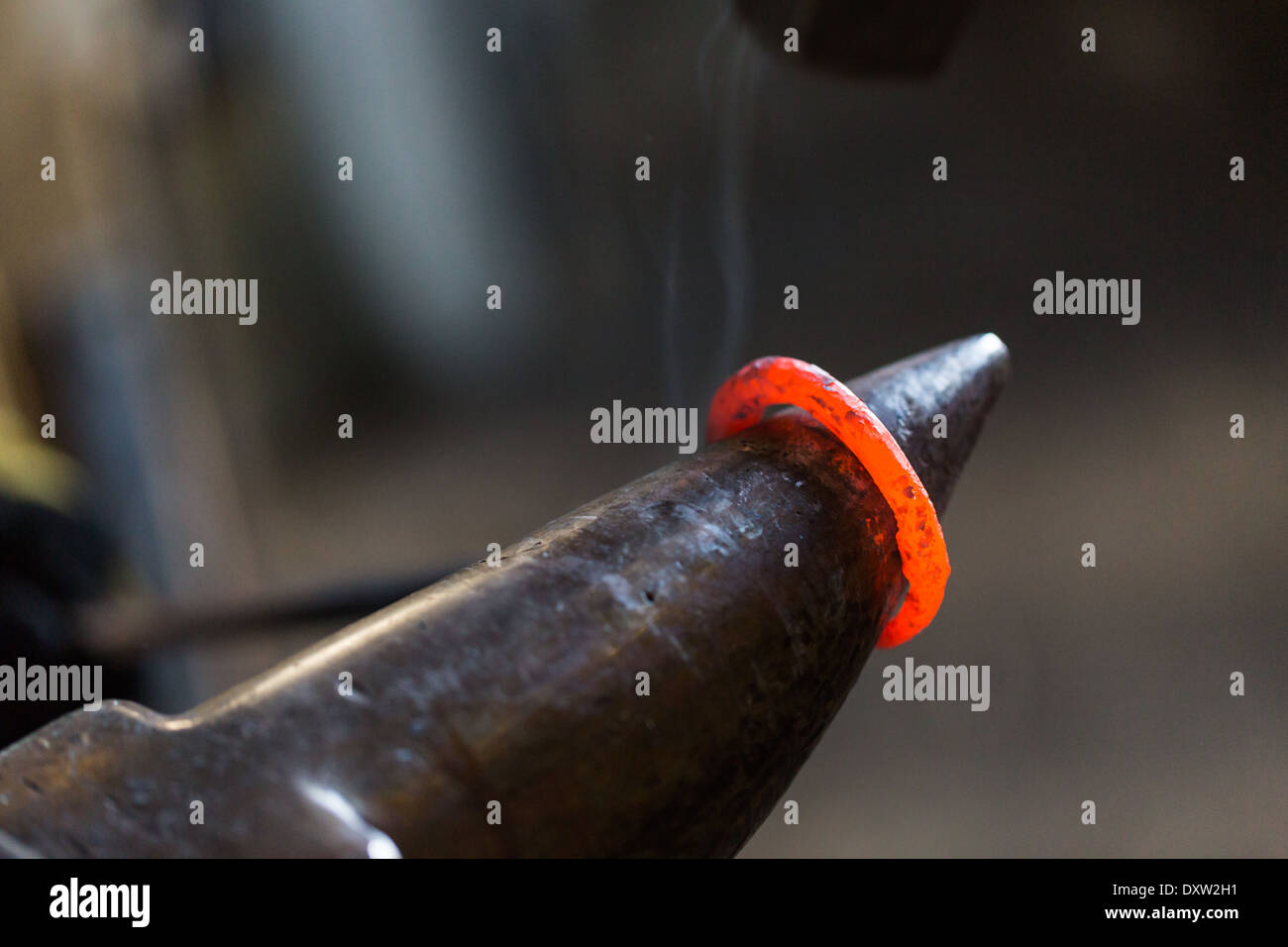 blacksmith bending hot iron on the anvil Stock Photo - Alamy