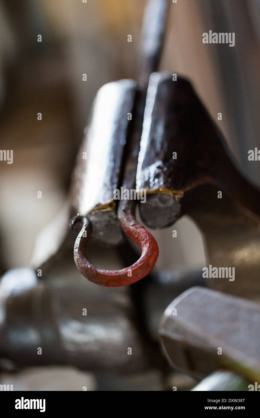 blacksmith bending hot iron on the anvil Stock Photo - Alamy