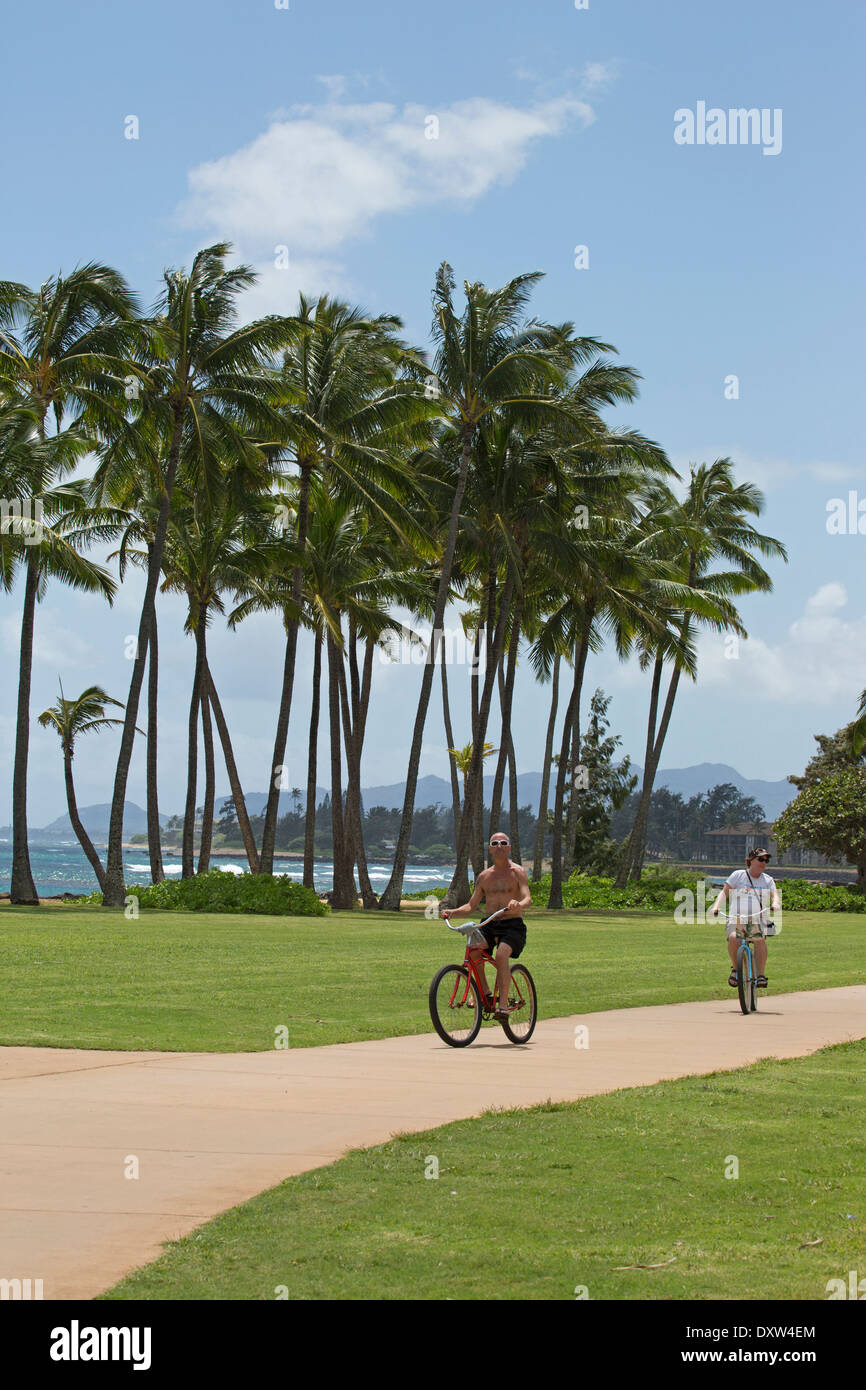 Man and woman cycling on shared use Kauai path along the Pacific coast ...