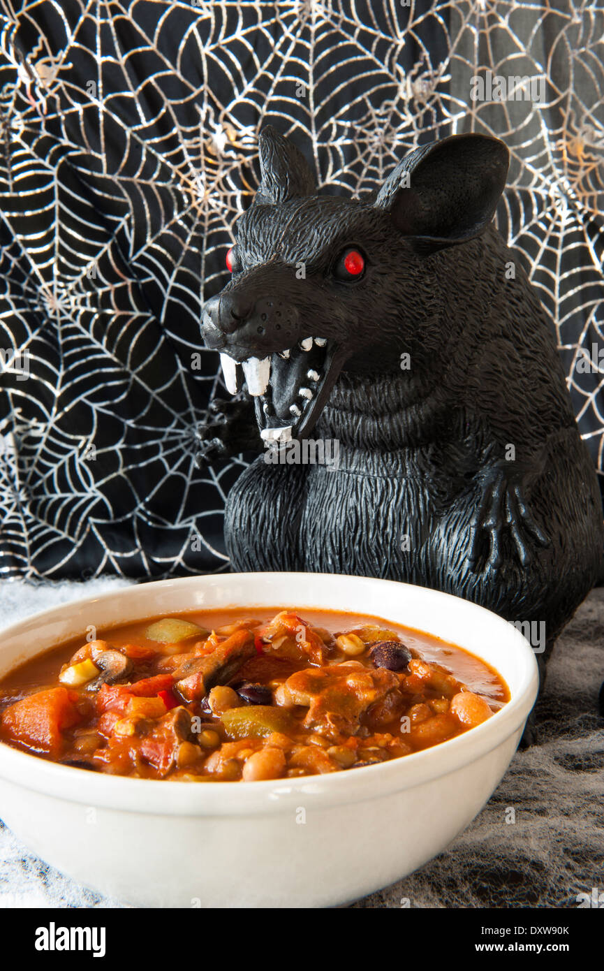 Hungry Halloween rat eating a bowl of vegetarian chili Stock Photo - Alamy