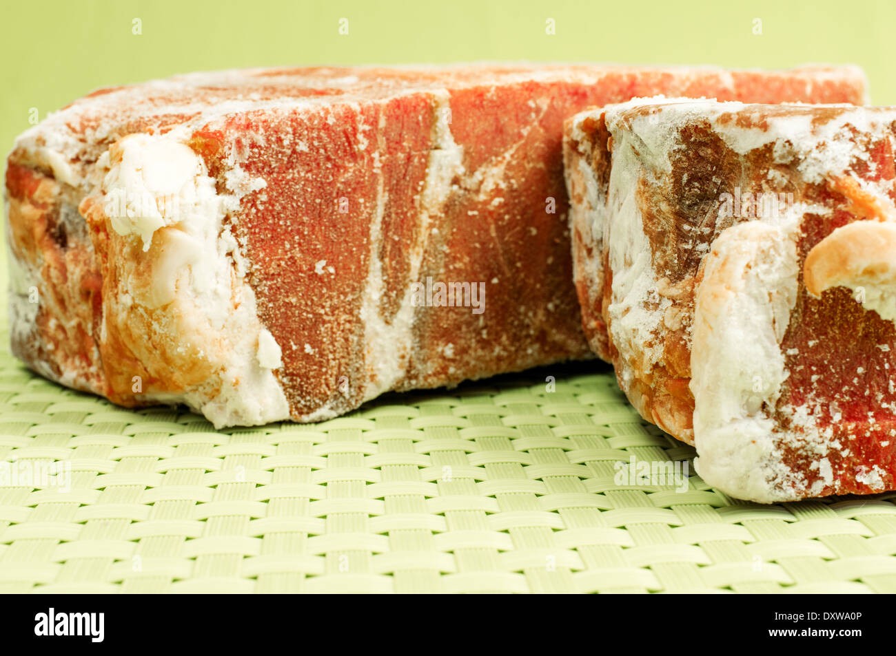 Frozen meat. Two pieces of frozen beef meat on a green background Stock ...