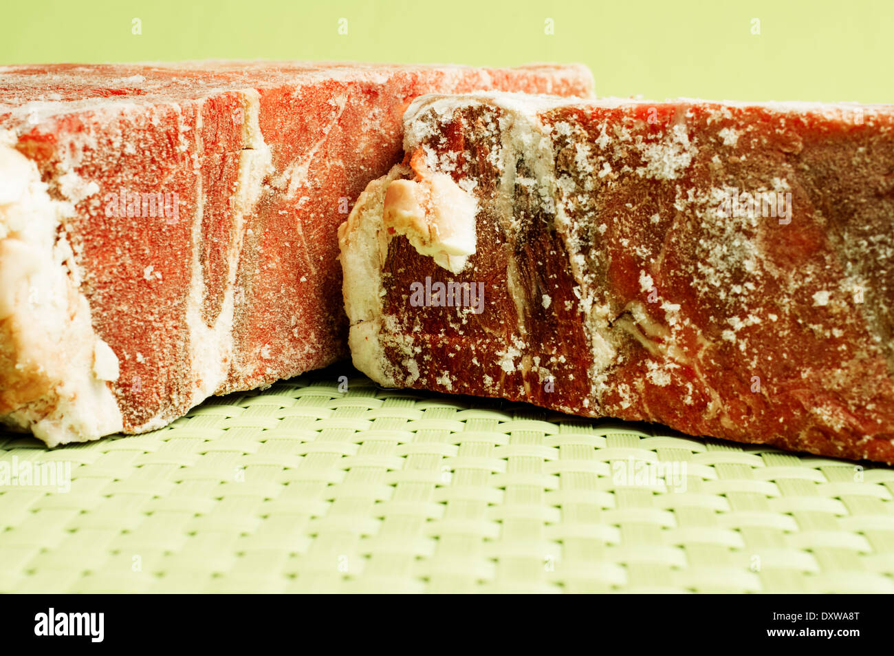 Frozen meat. Two pieces of frozen beef meat on a green background Stock ...