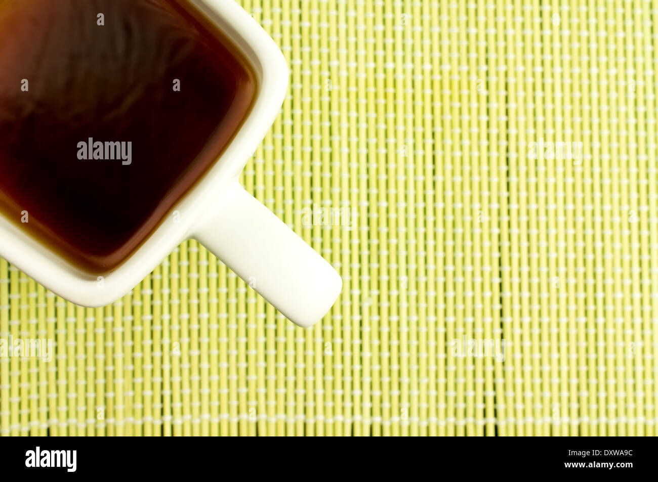 White square cup of tea. Background of green bamboo mat. View from ...