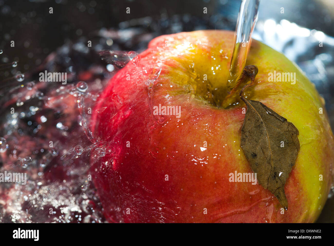 washing apple - red apple being washed under a jet of water, frozen ...