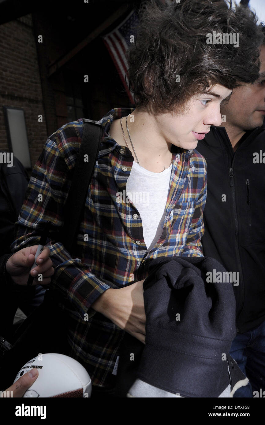 Harry Styles of One Direction is helped to his car by a security guard ...