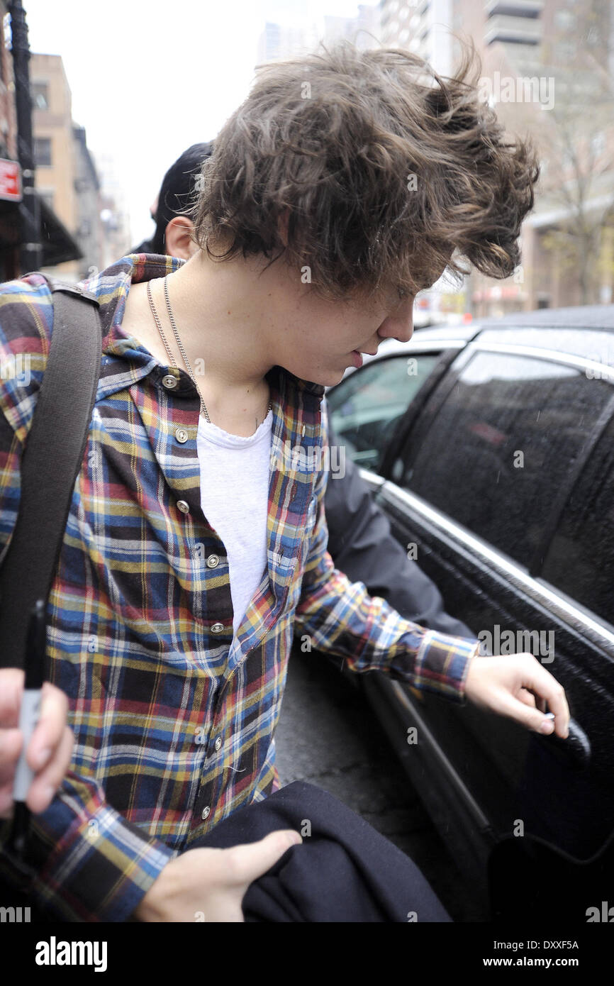 Harry Styles of One Direction is helped to his car by a security guard ...
