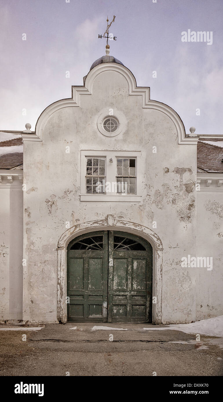 An old stucco arched building from the guilded age with peeling paint ...