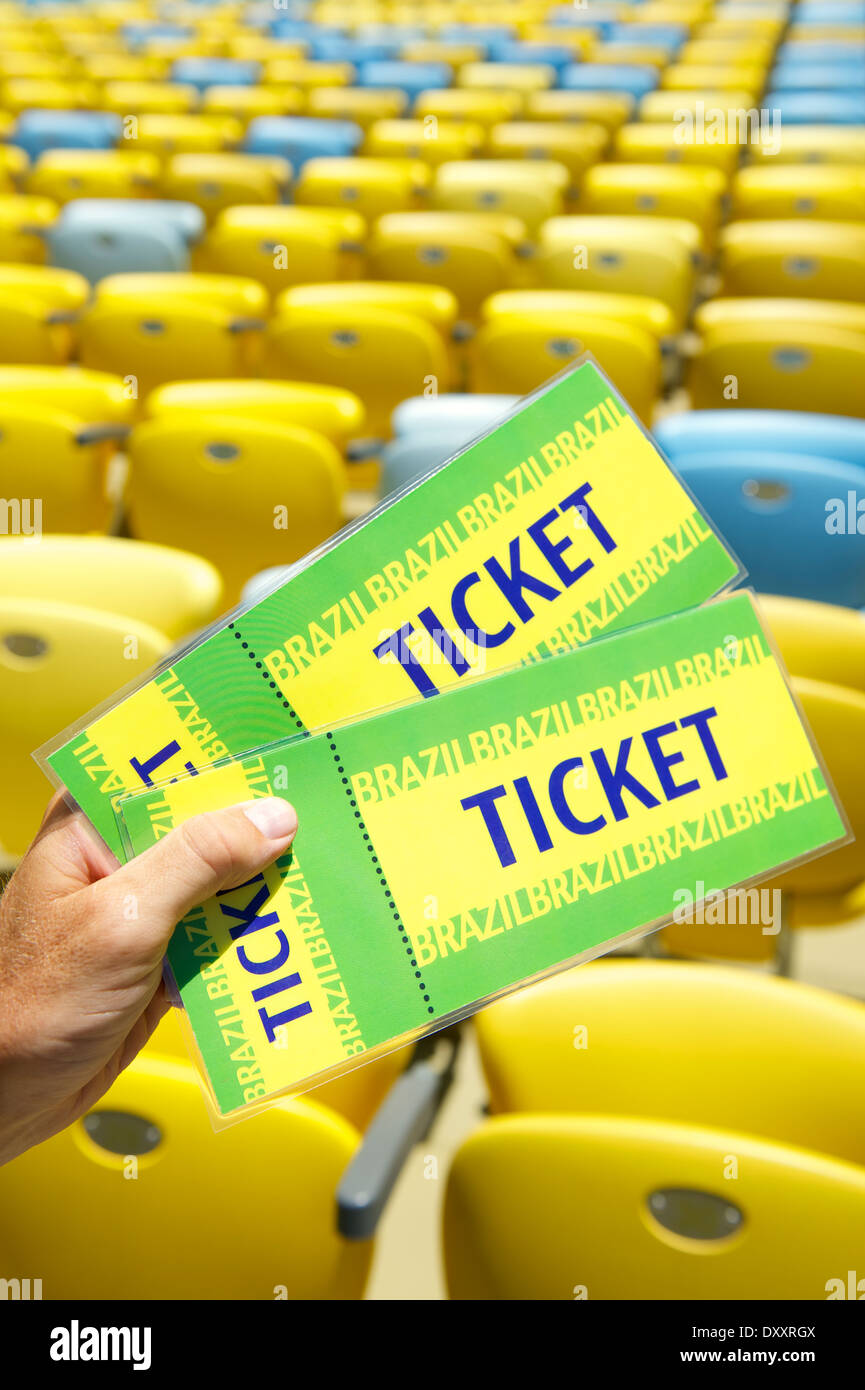 Soccer fan holding two Brazil tickets in front of empty stadium seats ...