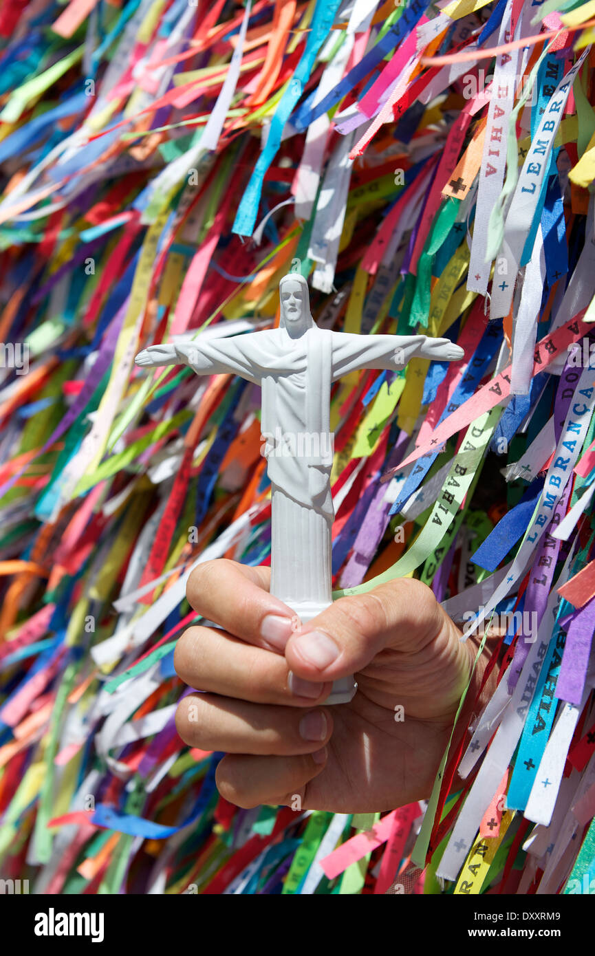 Hand holding Christ the Redeemer religious souvenir in front of wall of ...