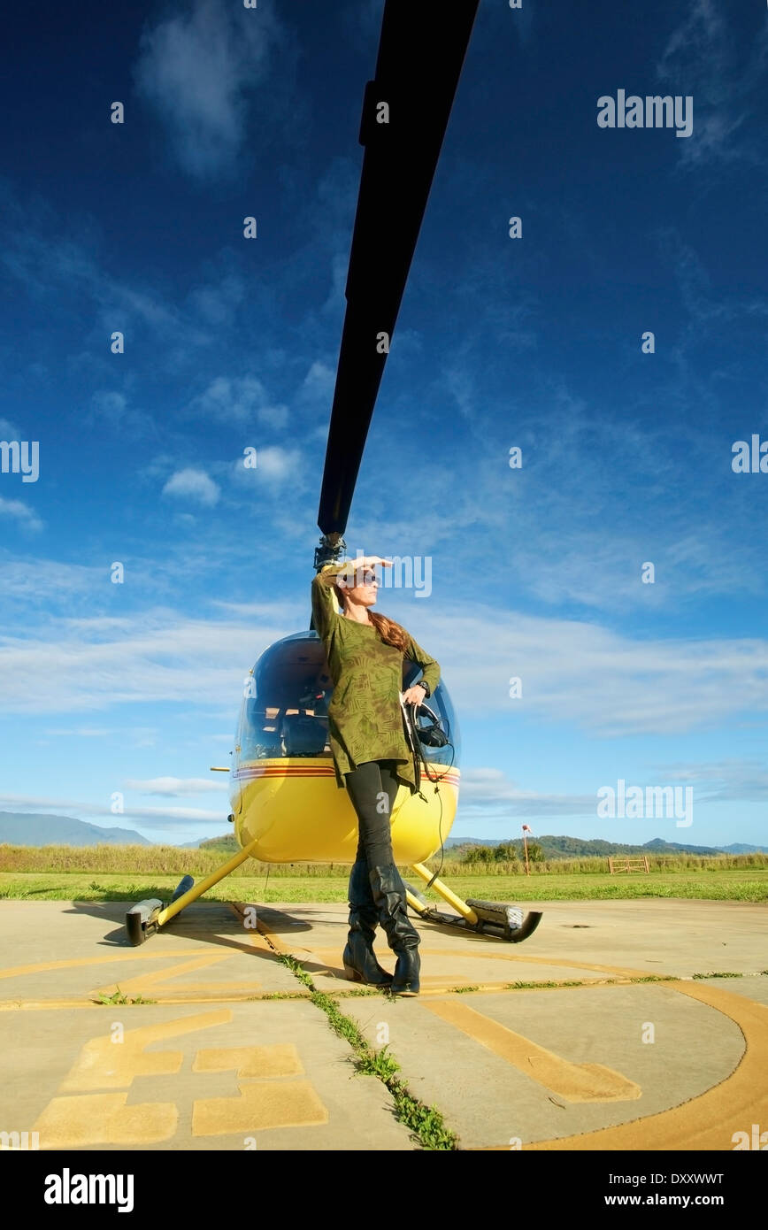 A pilot stands waiting with a helicopter on a landing pad; Kilauea ...