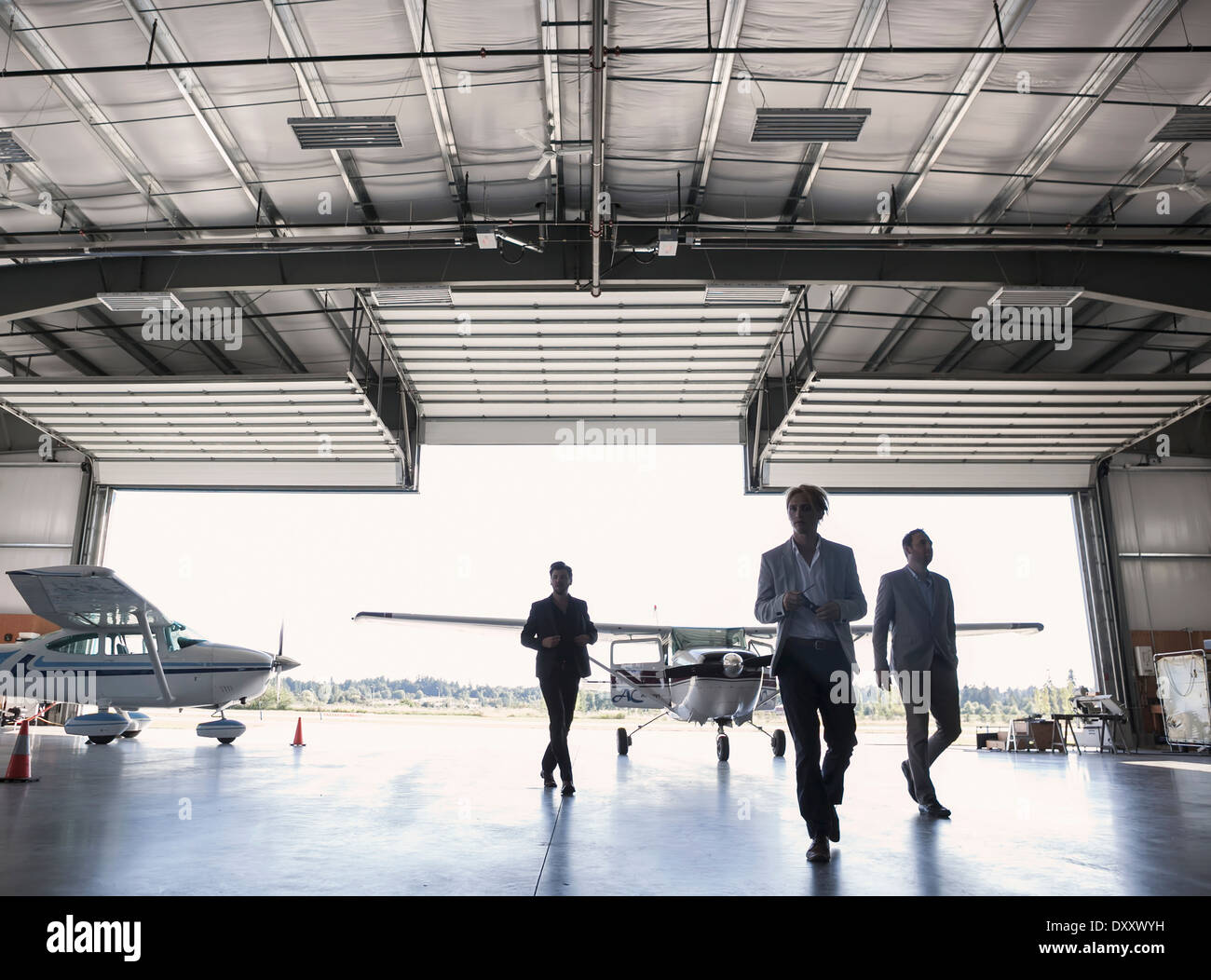 Three businessmen entering airplane hangar; Langley, British Columbia ...