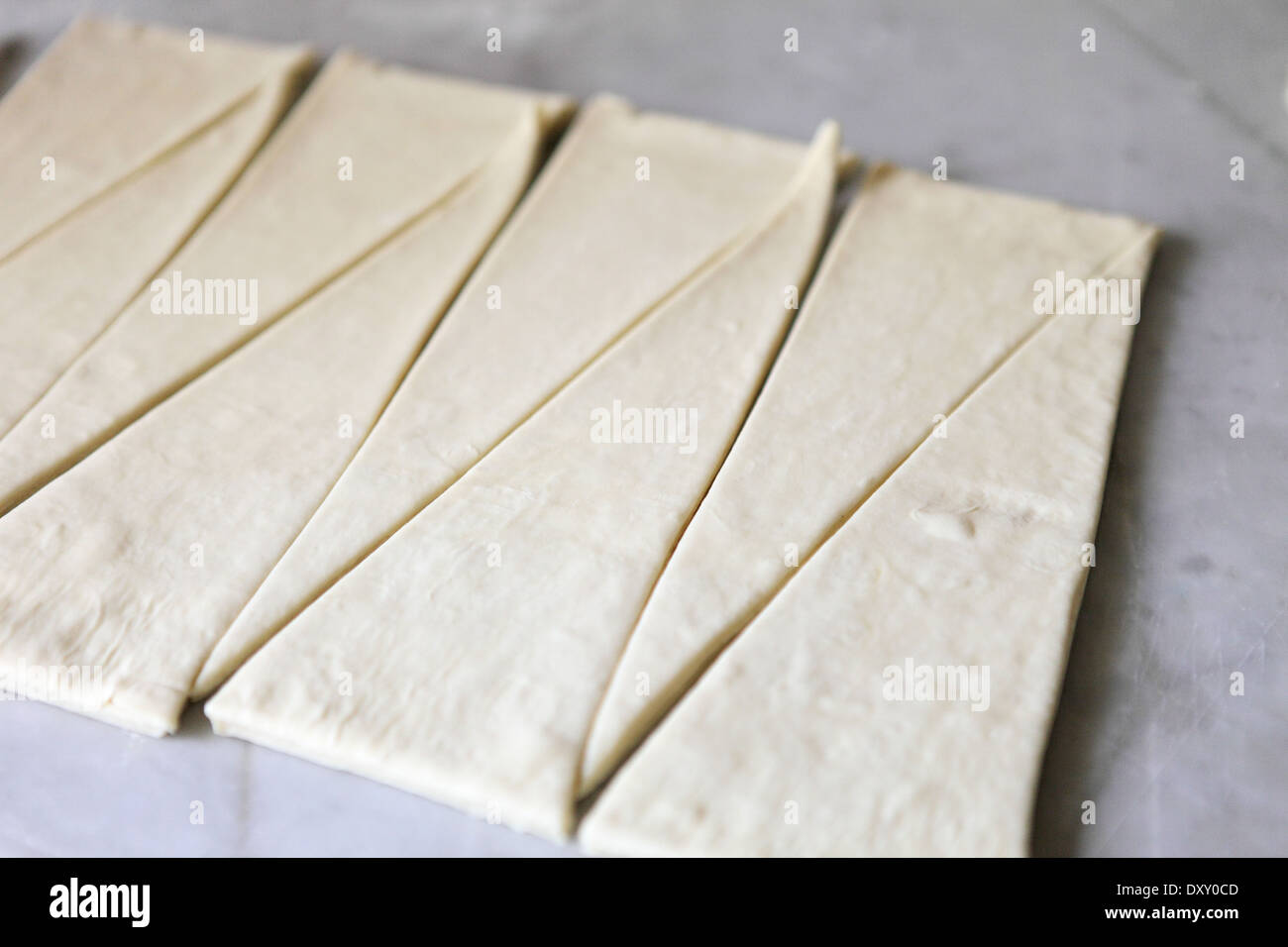Uncooked flaky pastry cut in triangles Stock Photo - Alamy