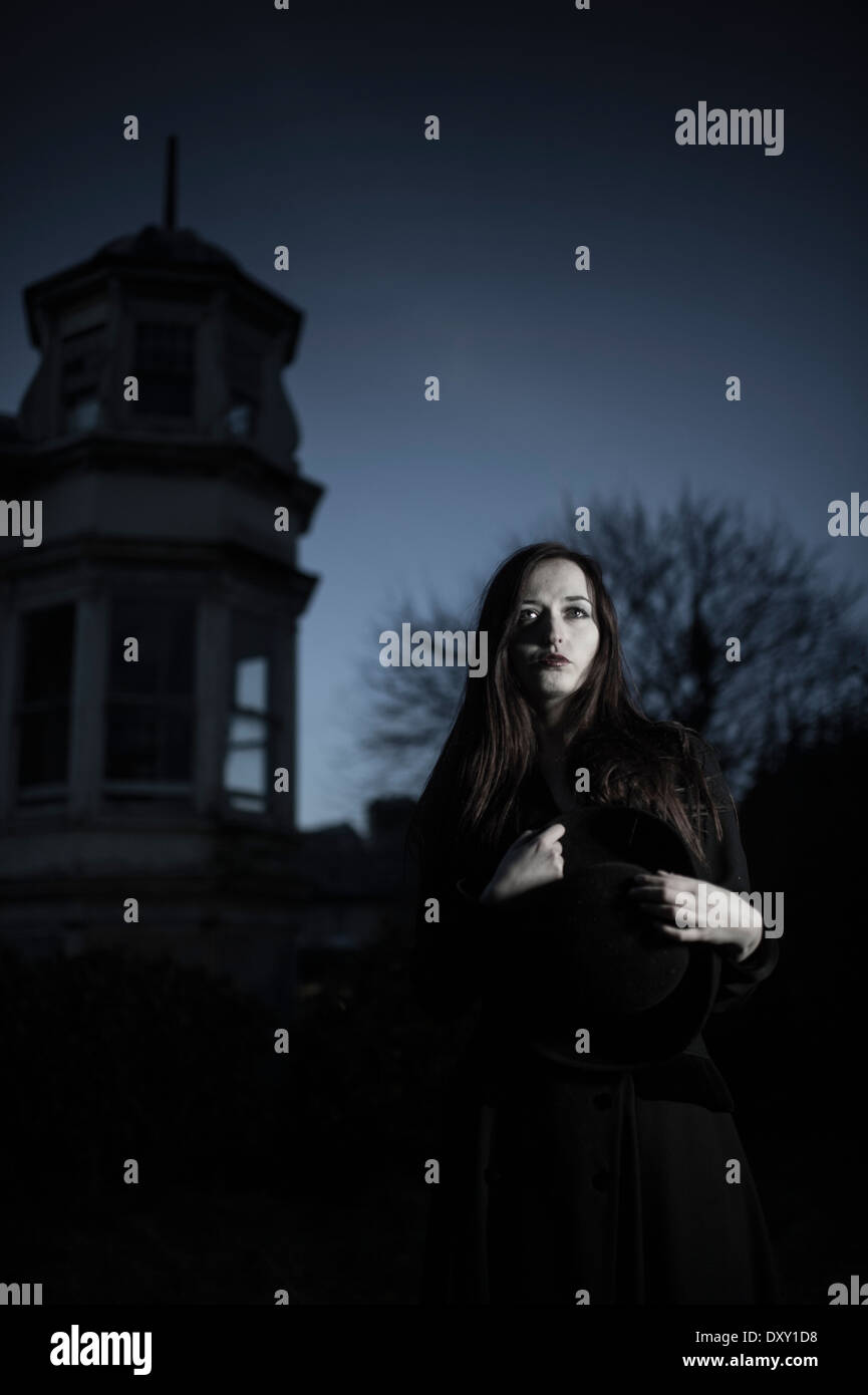 A Young woman outside alone, abandoned ruined Gothic house building ...