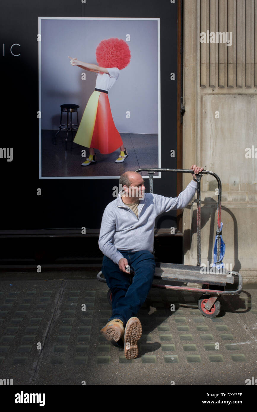 A removals man rests on a collection trolley beneath a fashion model ...