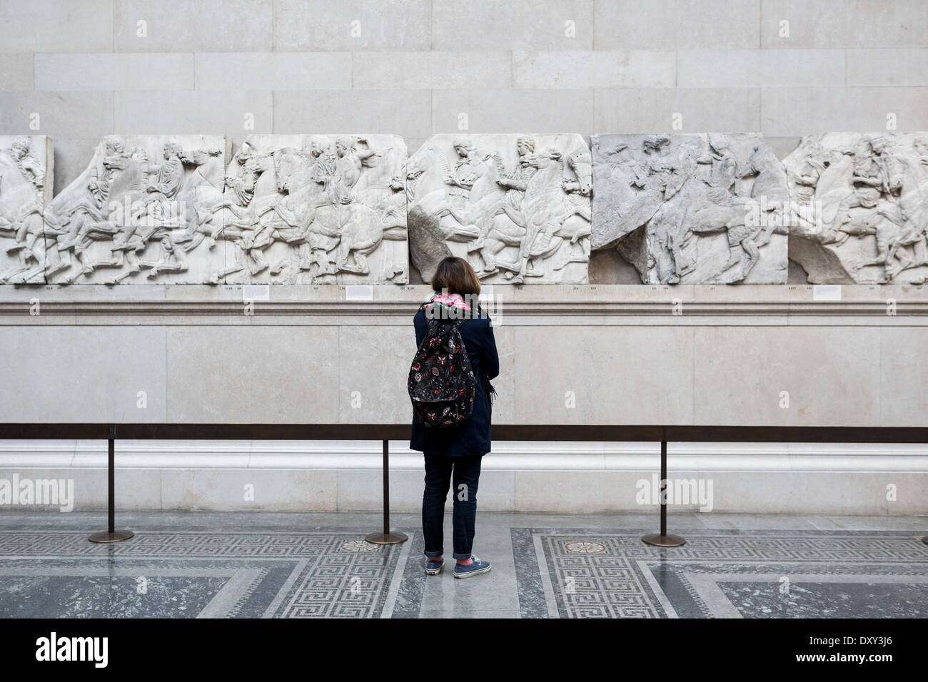 A tourist looks at a section of a frieze from the Elgin Marbles ...