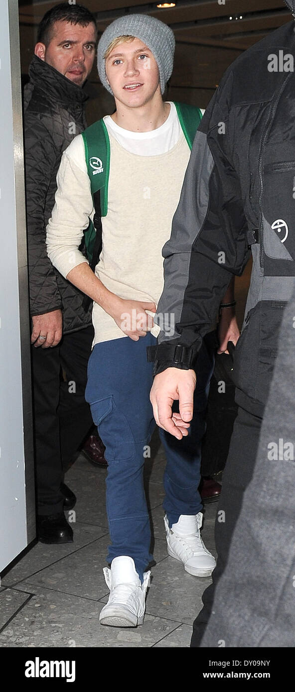 One Direction arrive at a manic Heathrow Terminal 5 holding giant ...
