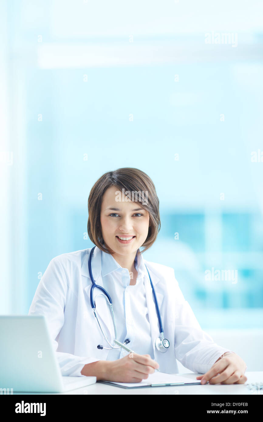Vertical portrait of a young female doctor looking at camera at her ...