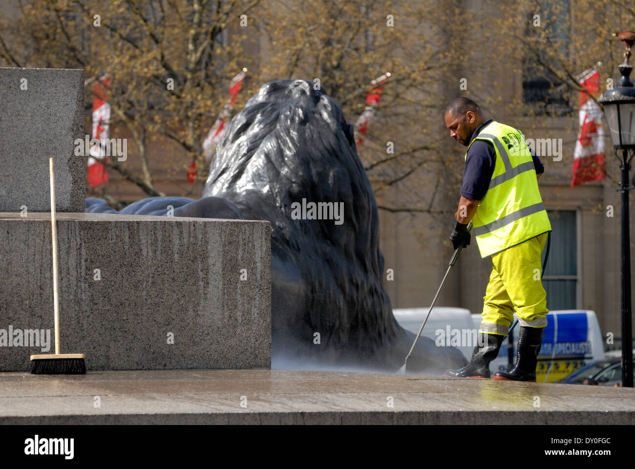 London, England, UK. Worker in hi-vis jacket cleaning the base of ...