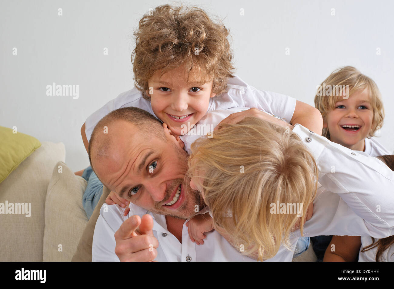 Children climbing over their father on the sofa Stock Photo - Alamy