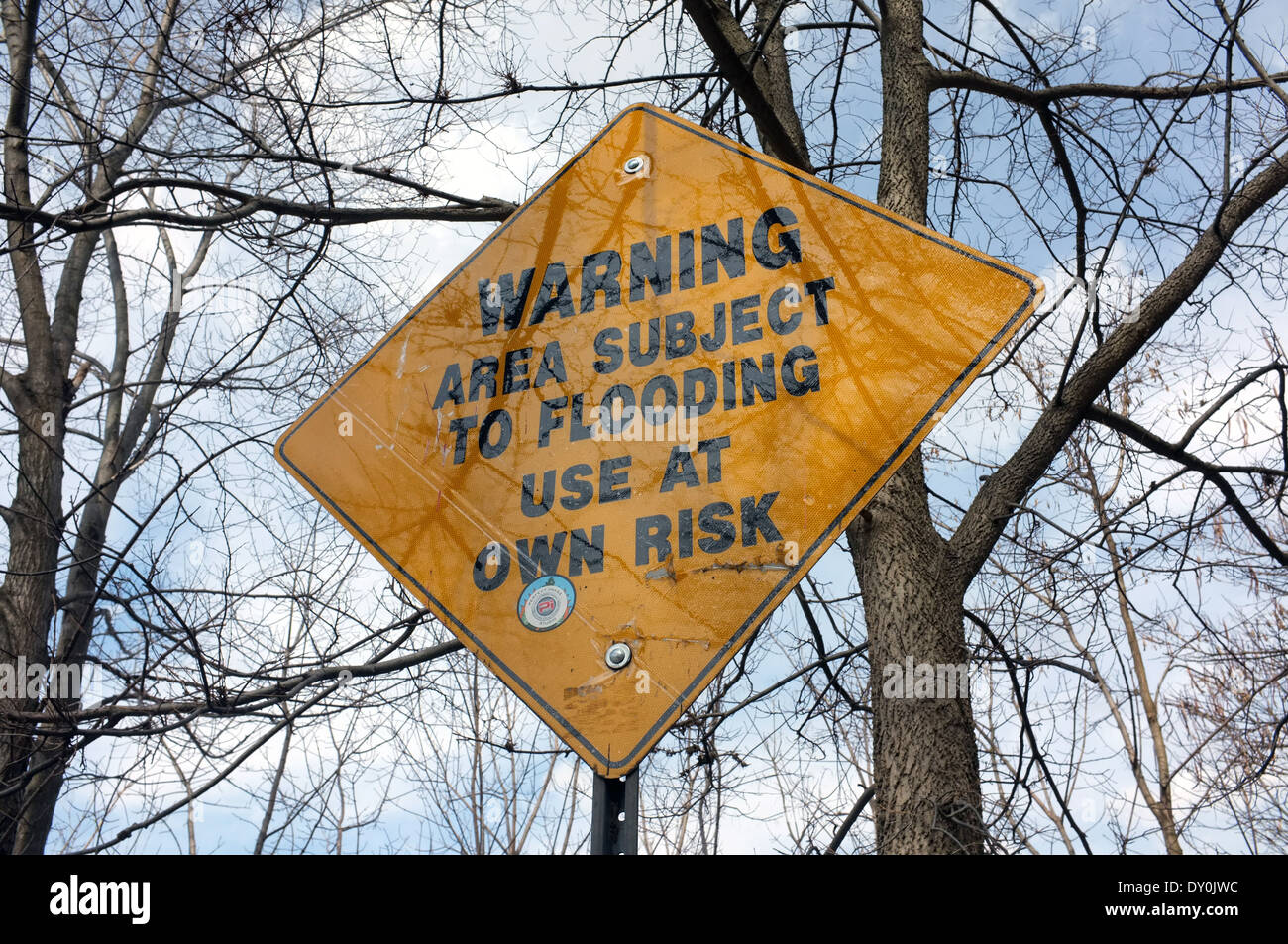 A flooding warning sign underneath trees by a river Stock Photo - Alamy