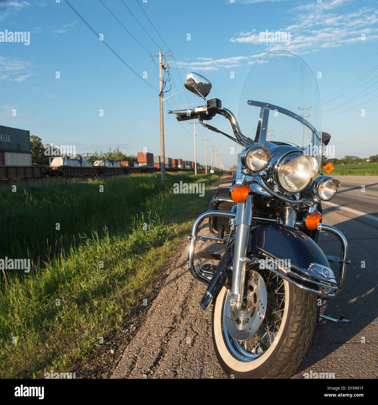 A motorcycle parked on the roadside with a train traveling by; Manitoba ...