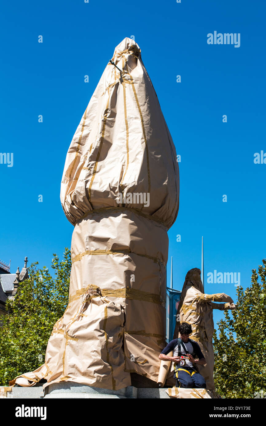 Artist covering a statue with brown paper as part of an art project ...