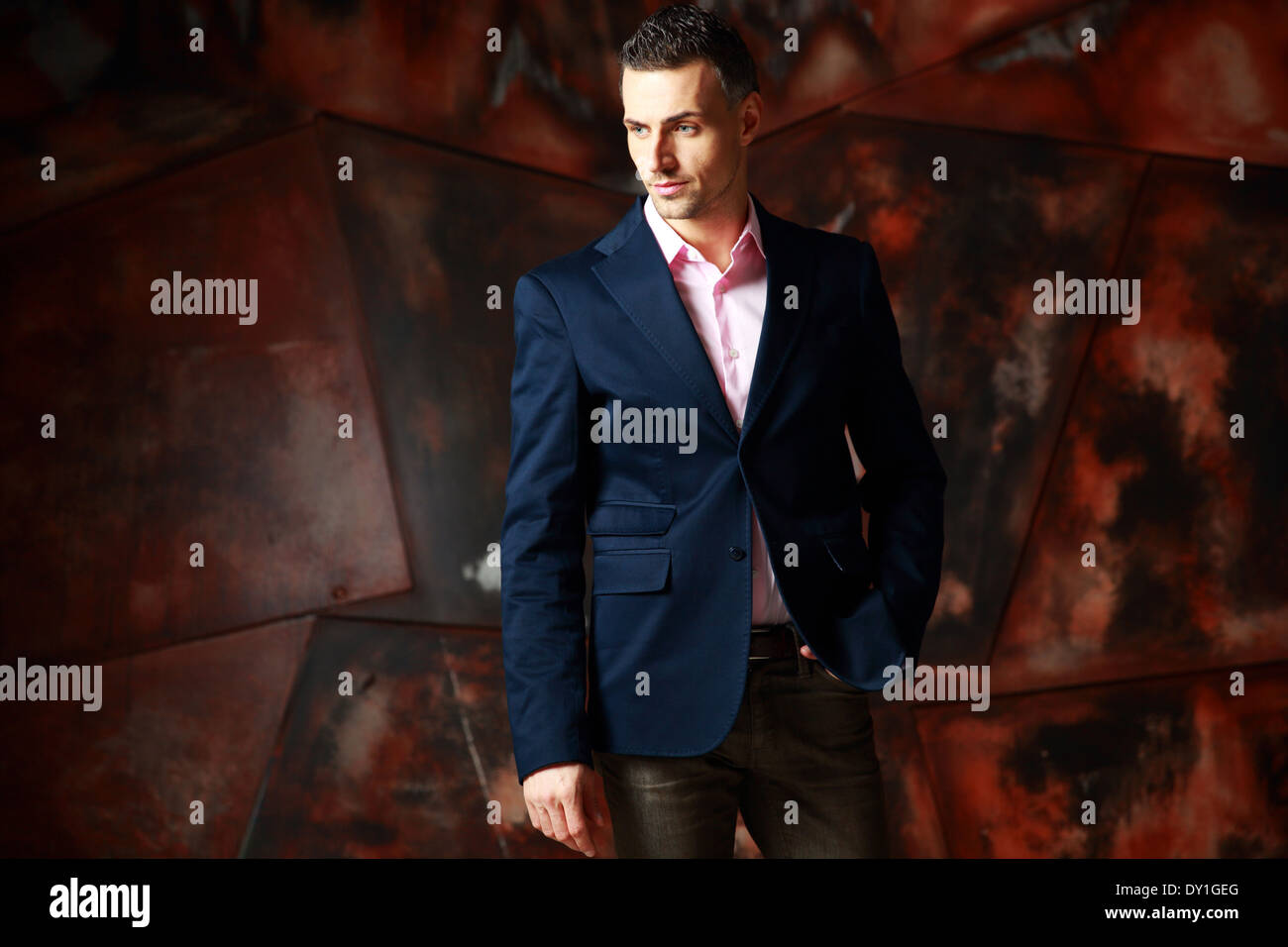 Cool fashion man standing and looking away over industrial background ...