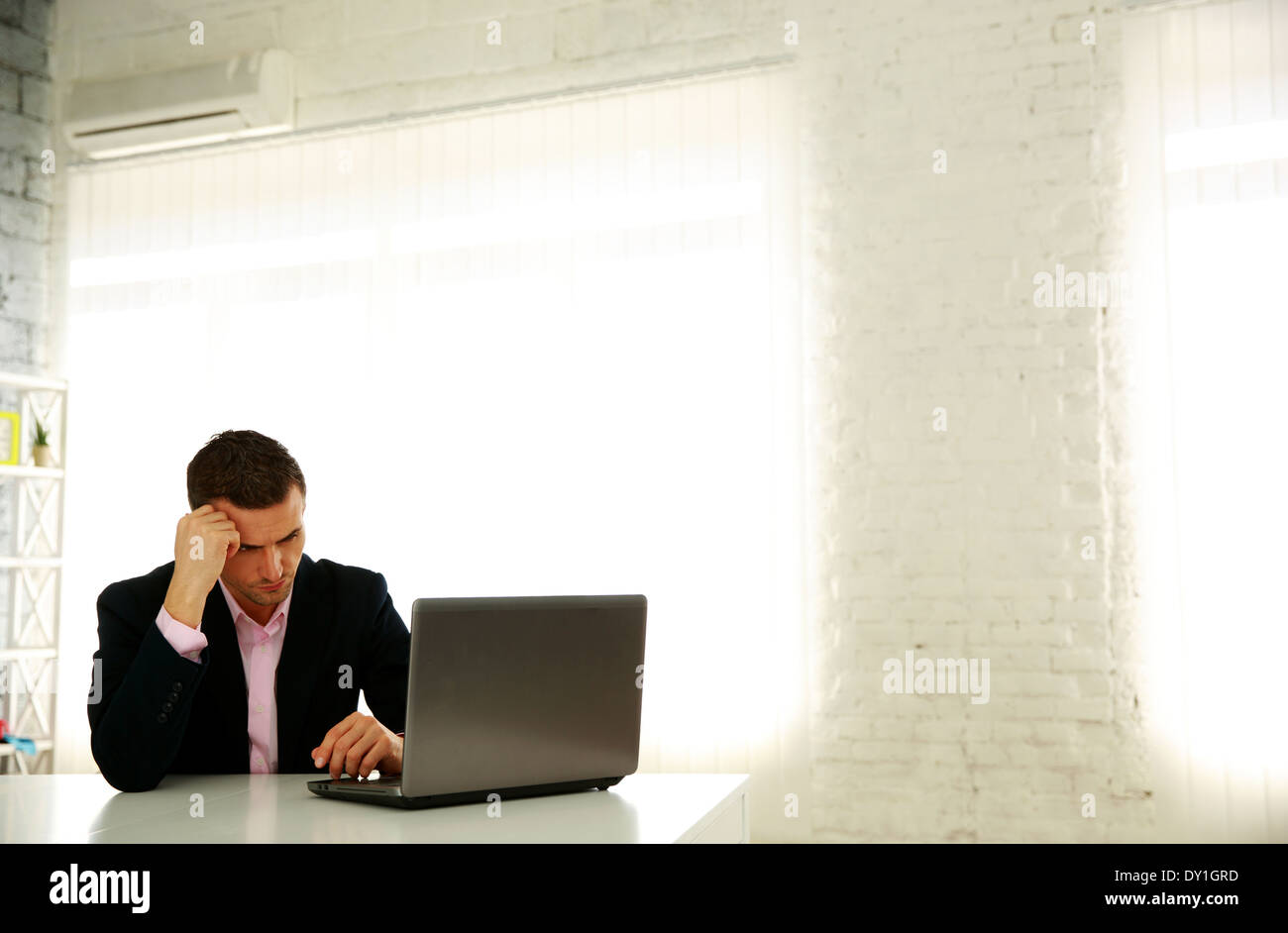 Confident businessman sitting at the table with laptop in office Stock ...