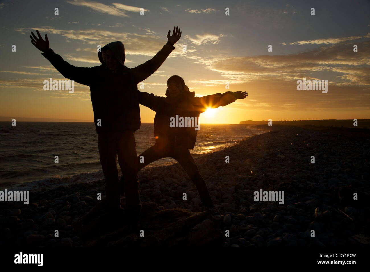 Two boys make star shape with backdrop of sea at sunset, Limpert Bay ...